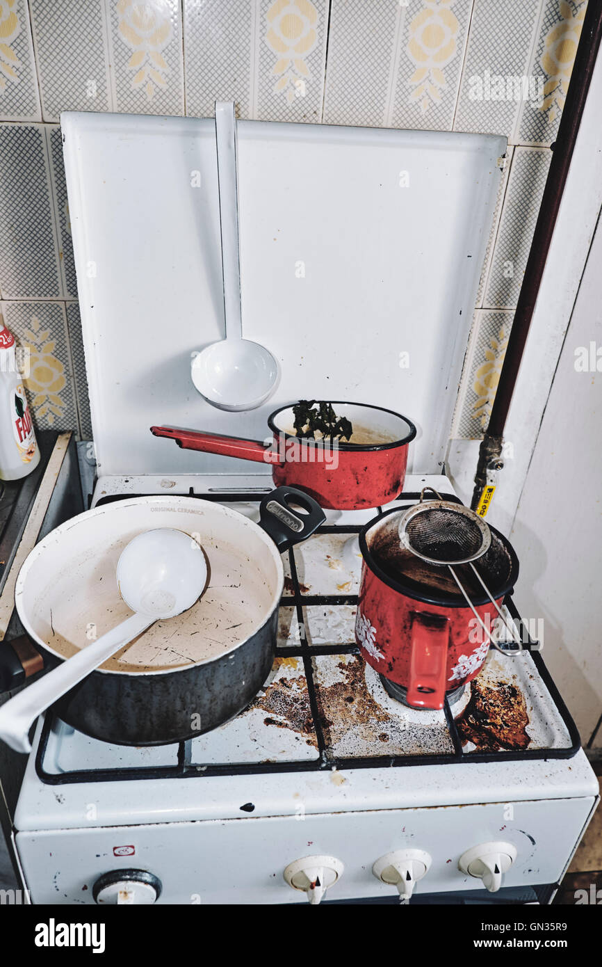 A disorganized stove featuring dirty pots, pans, and cooking utensils ...