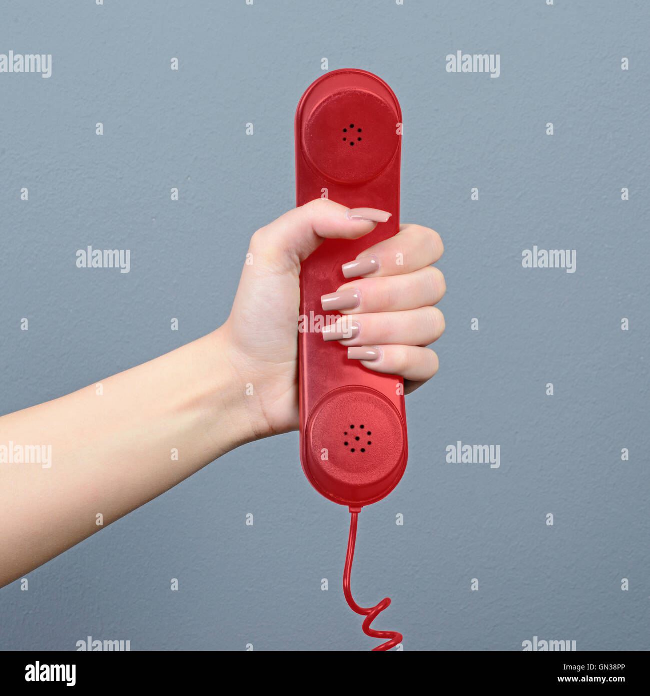 Hand holding red phone against gray background Stock Photo - Alamy