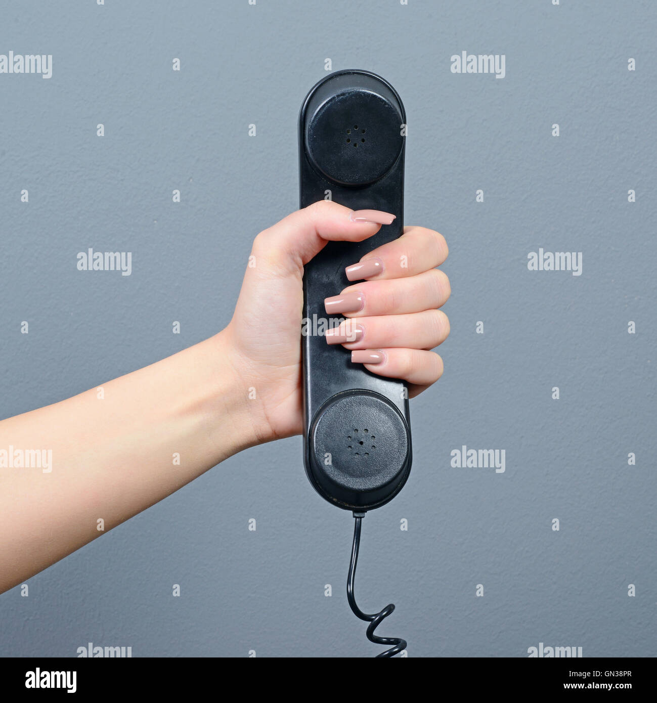 Hand holding telephone against gray background Stock Photo - Alamy