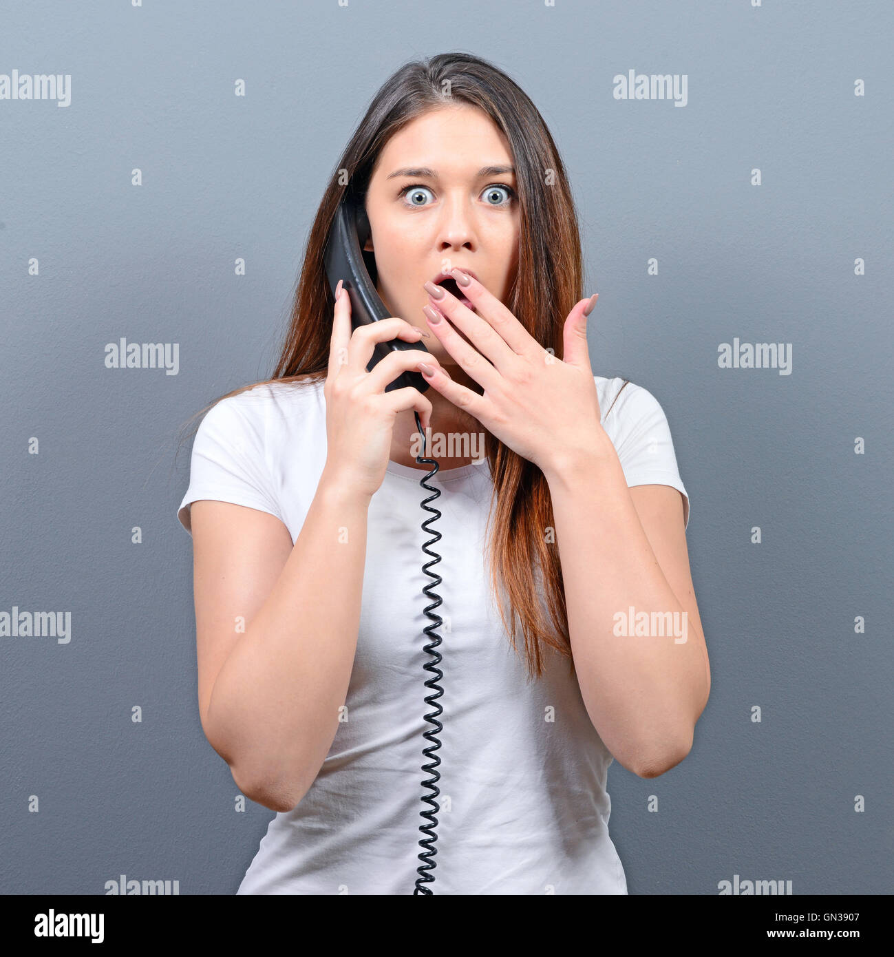 Portrait of woman having unpleasant phone calll against gray background ...