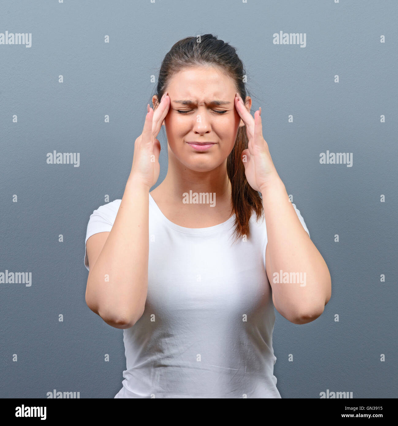 Portrait of woman with headache against gray background Stock Photo - Alamy