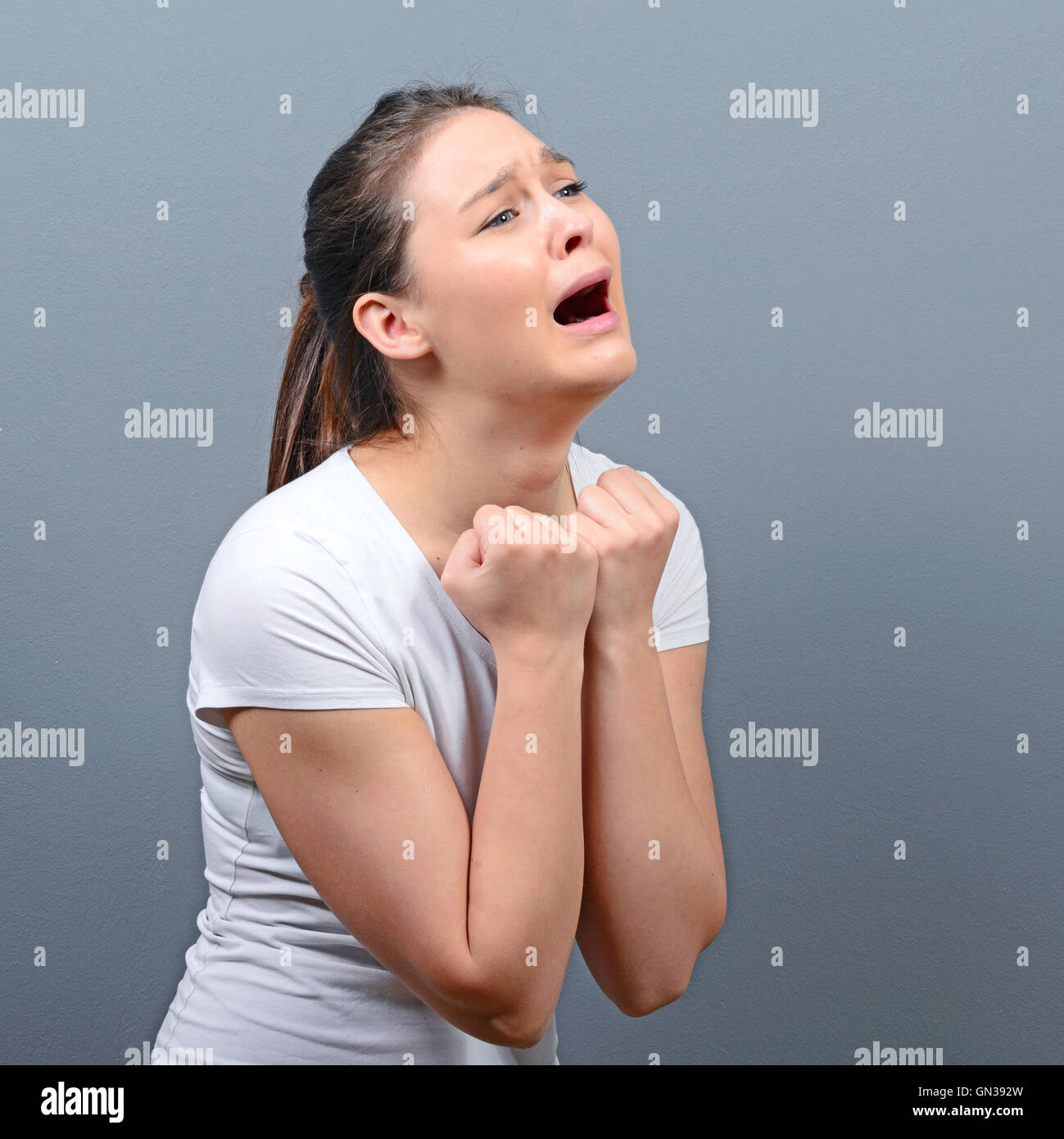 Woman praying about something or begging for mercy against gray ...