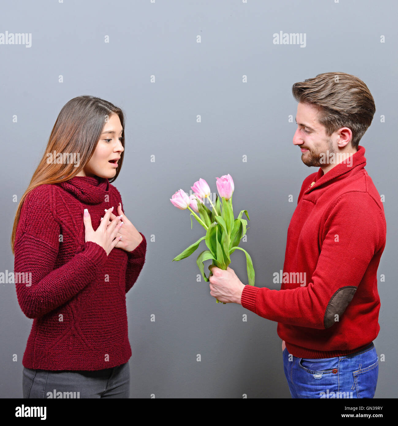 Portrait of happy young woman getting flowers from man and feeling ...