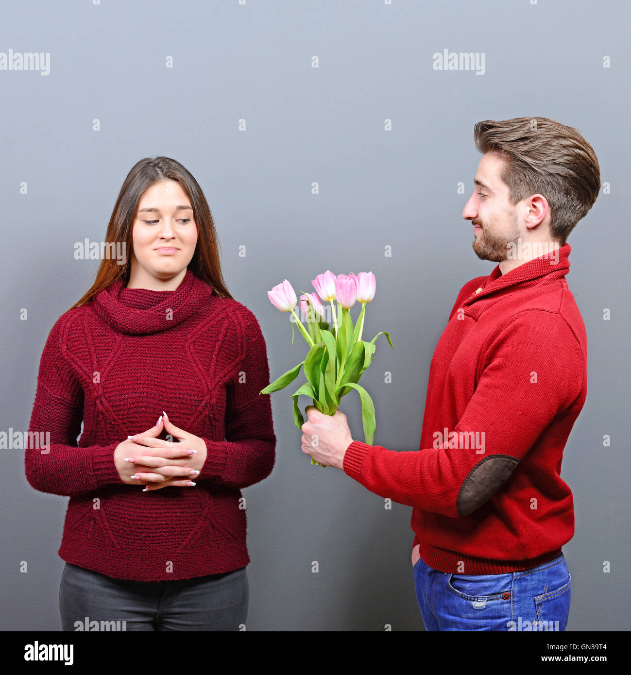 Portrait of unhappy young woman getting flowers from man she doesnt ...