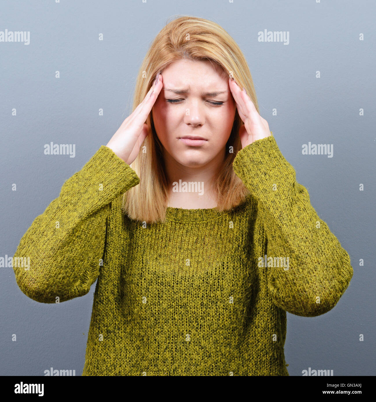 Portrait of woman with headache against gray background Stock Photo - Alamy