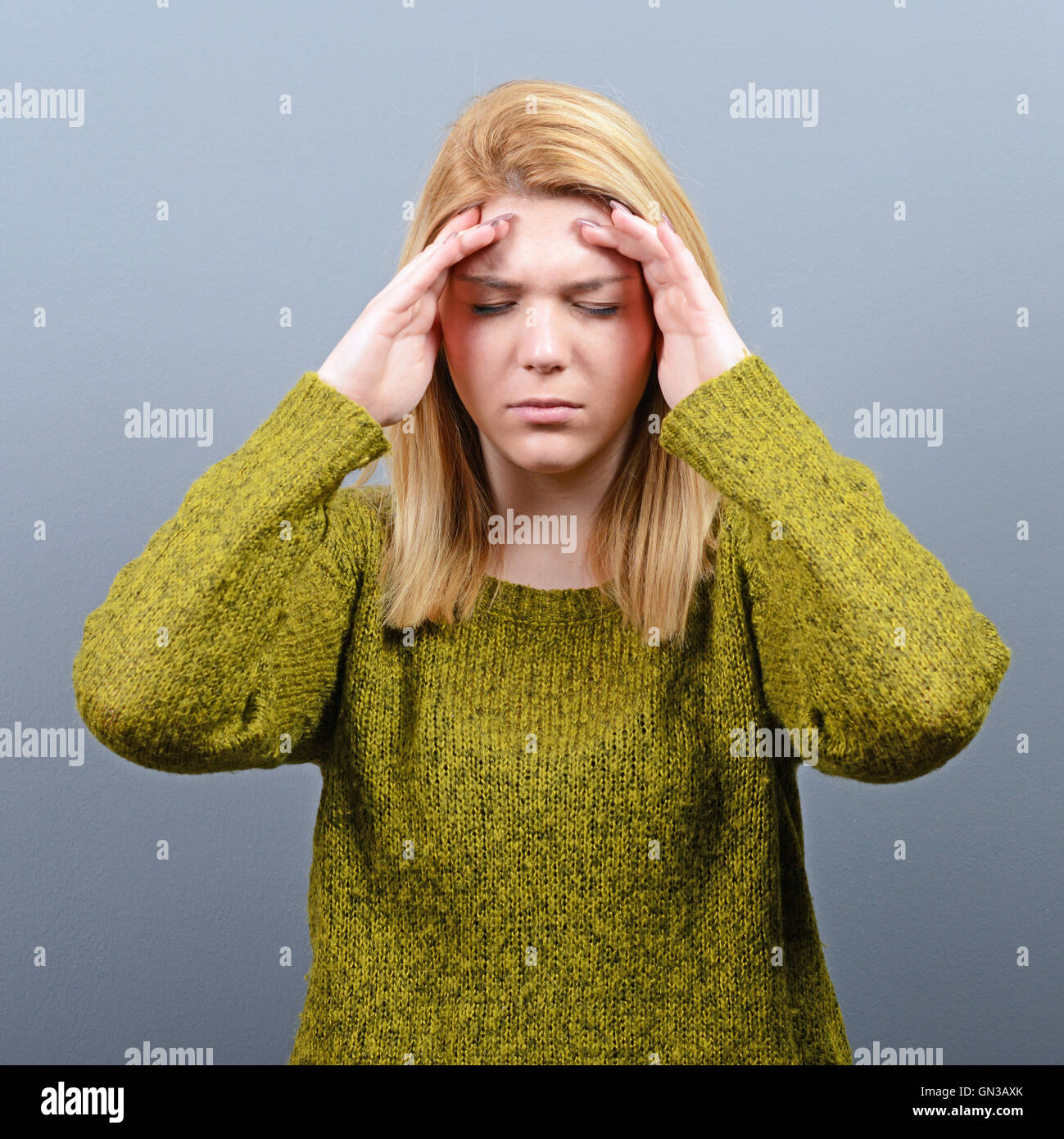 Portrait of woman with headache against gray background Stock Photo - Alamy