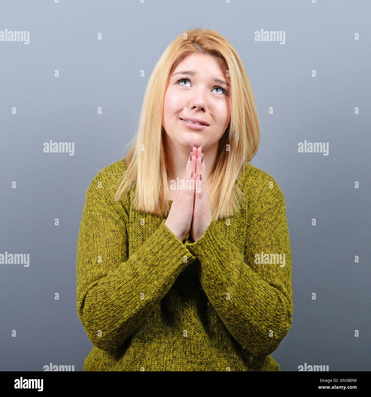 Woman praying about something or begging for mercy against gray ...