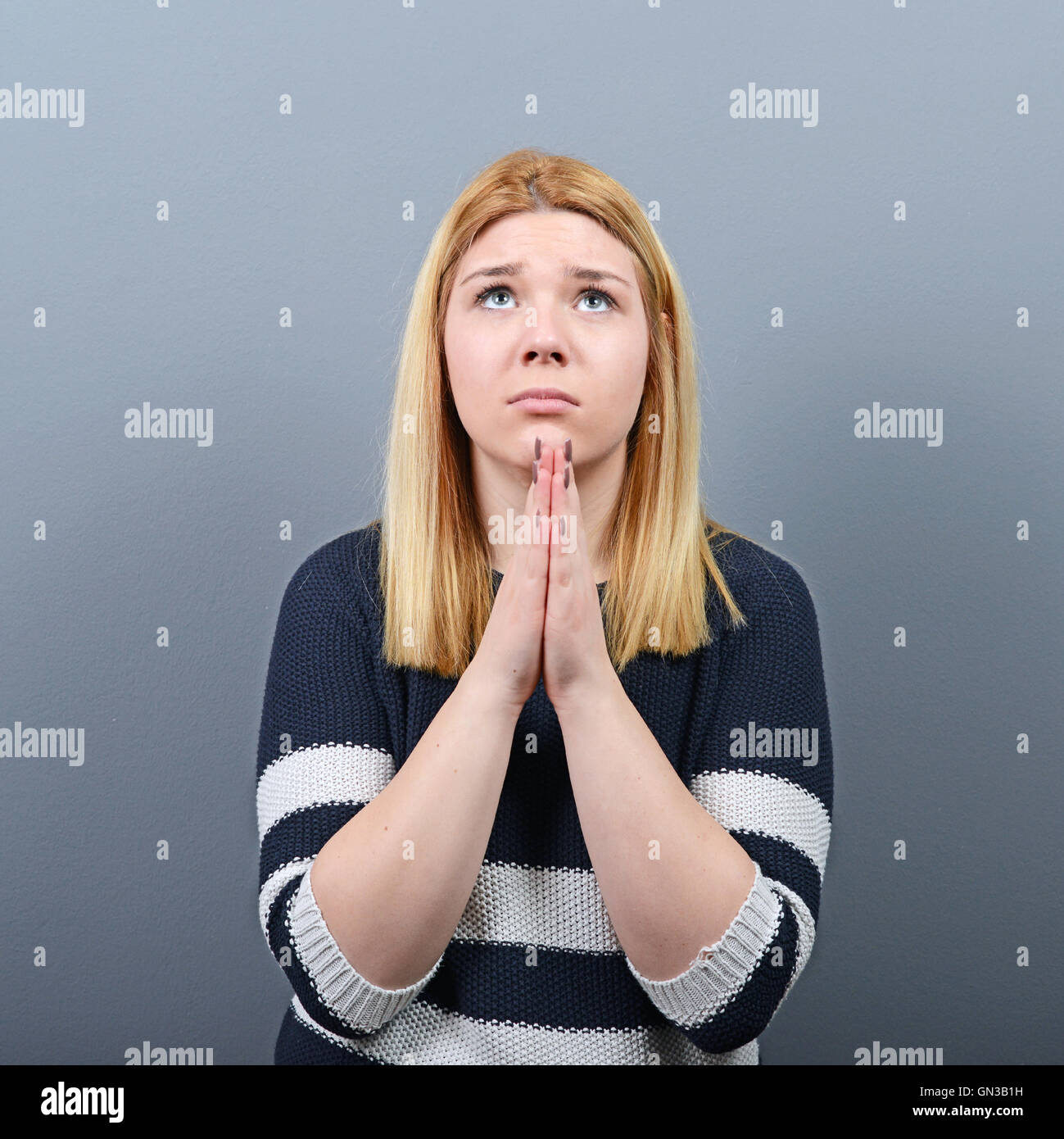 Woman praying about something or begging for mercy against gray ...