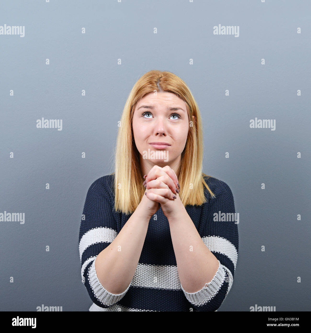 Woman praying about something or begging for mercy against gray ...