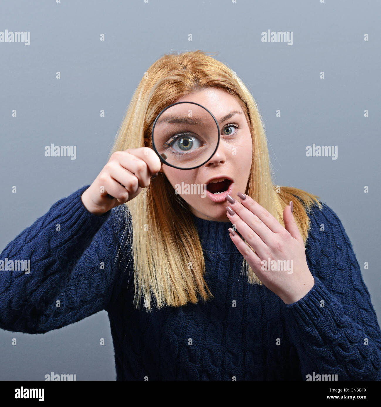 Woman with magnifying glass against gray background Stock Photo - Alamy