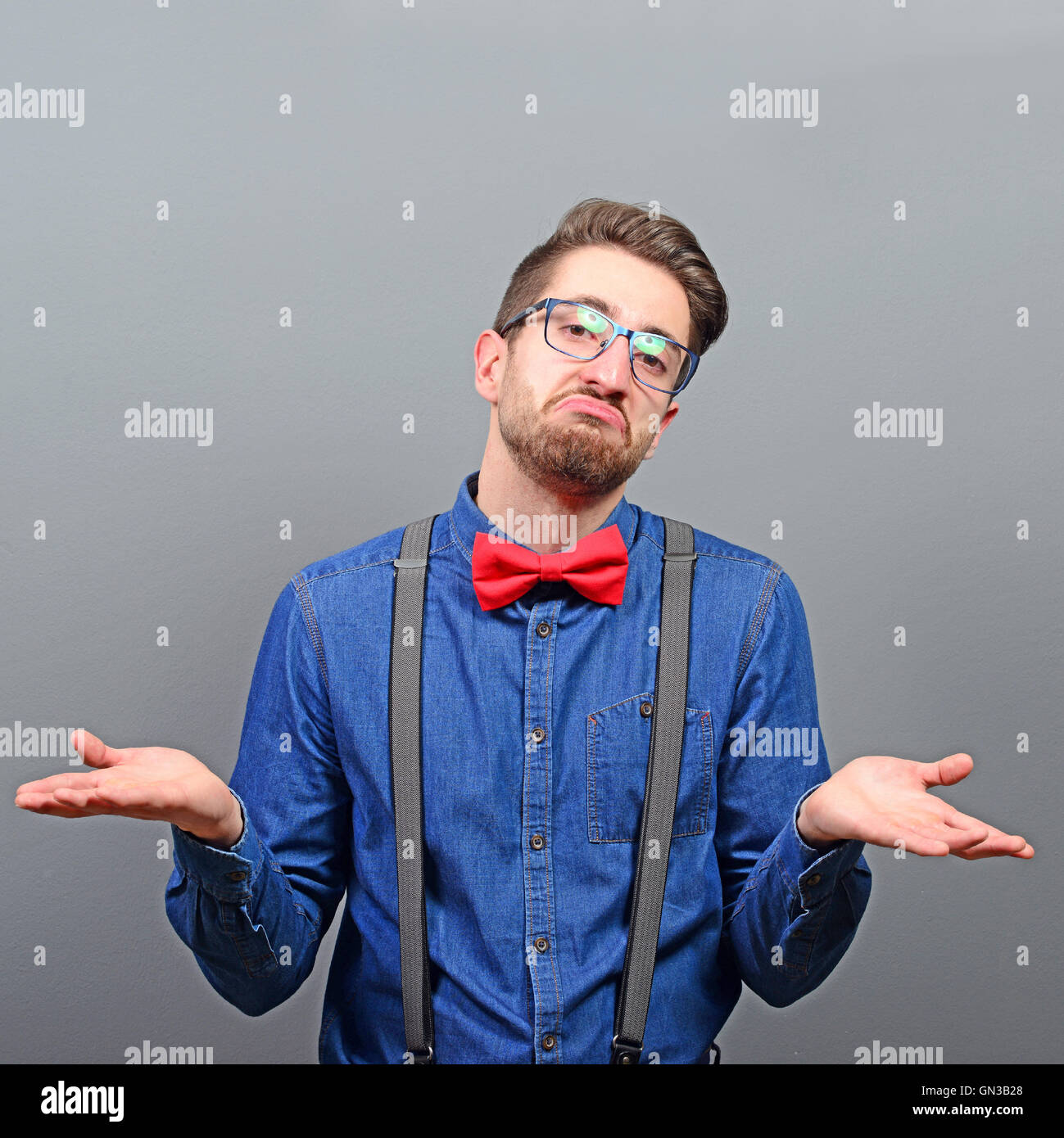 Portrait of a clueless man with spread hands against gray background ...