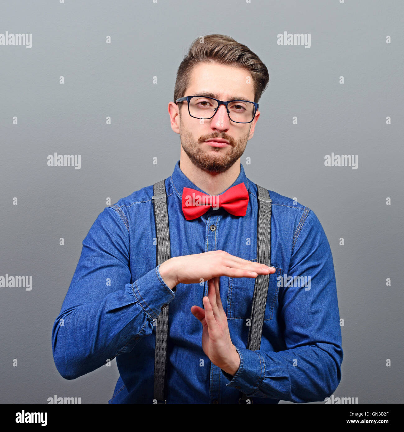 Portrait of a man showing time out gesture against gray background ...