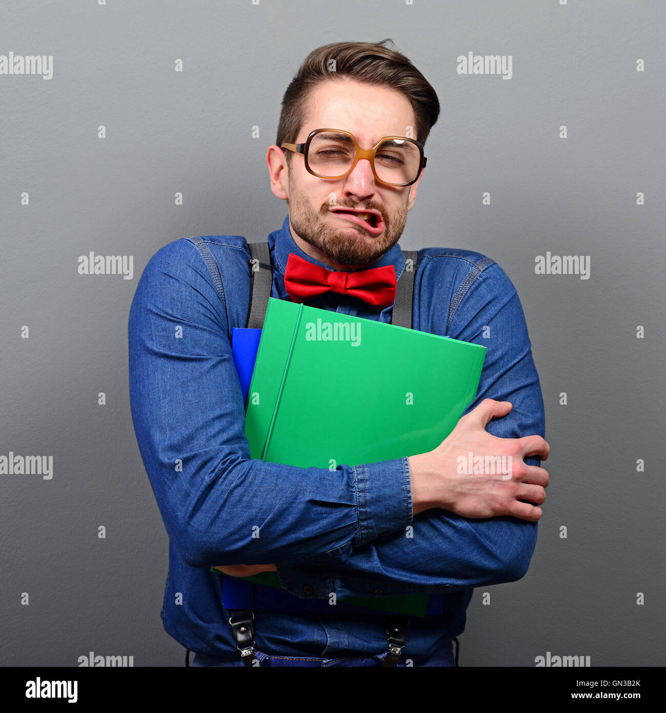 Portrait of a nerd holding books with retro glasses against gray ...