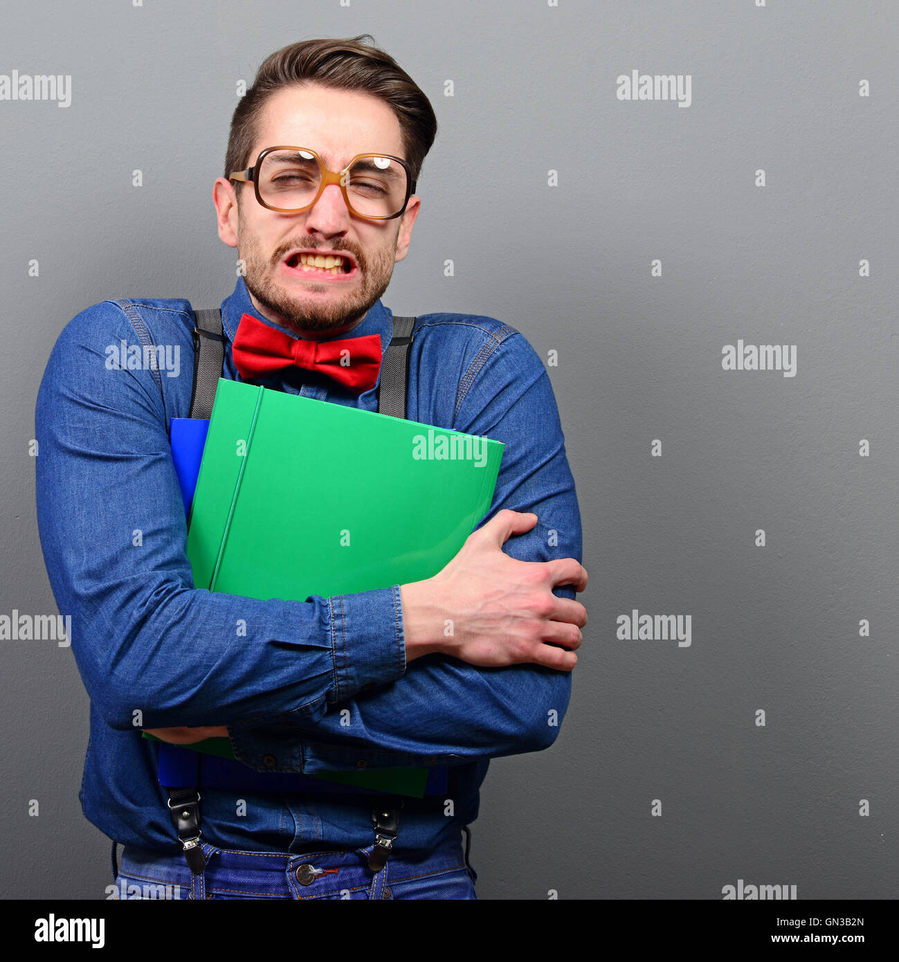 Portrait of a nerd holding books with retro glasses against gray ...