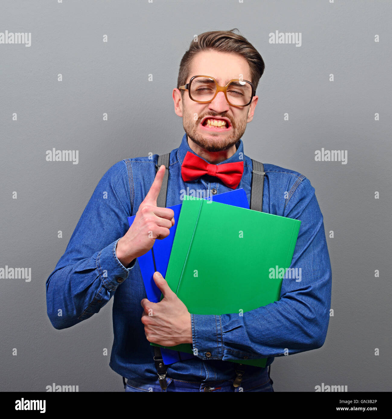 Portrait of a nerd holding books with retro glasses against gray ...