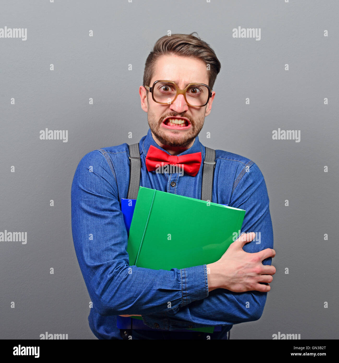 Portrait of a nerd holding books with retro glasses against gray ...