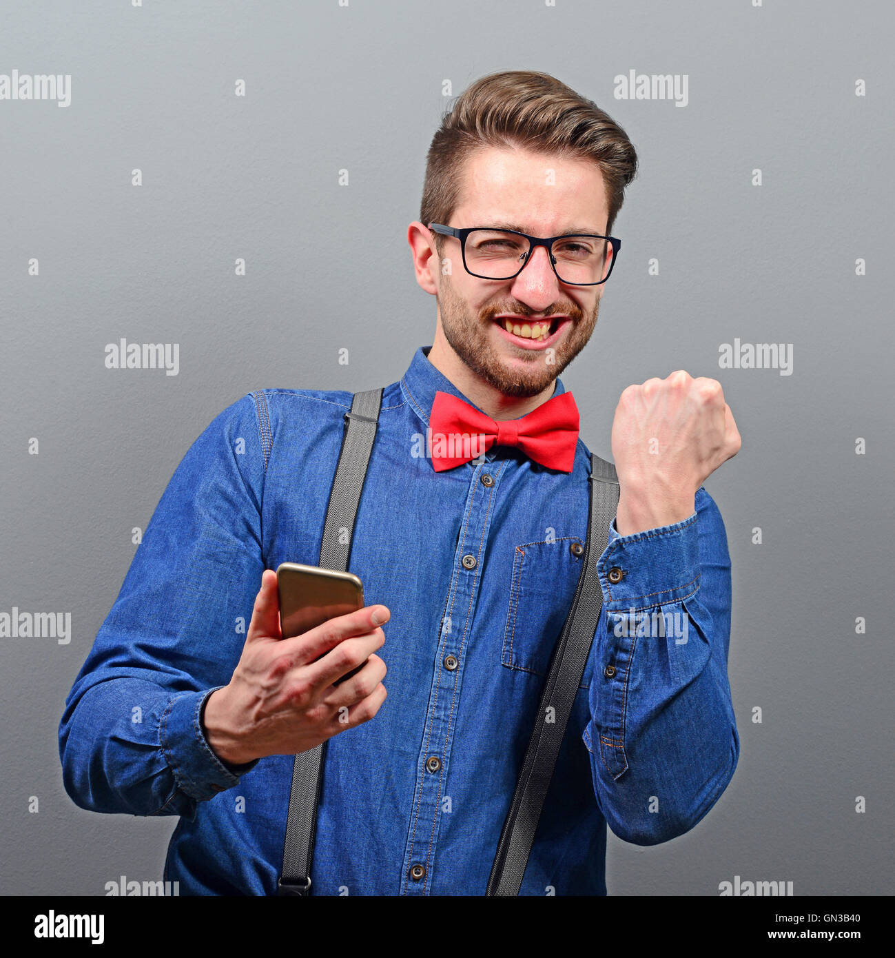 Portrait of ecstatic man holding cell phone and celebrating with closed ...