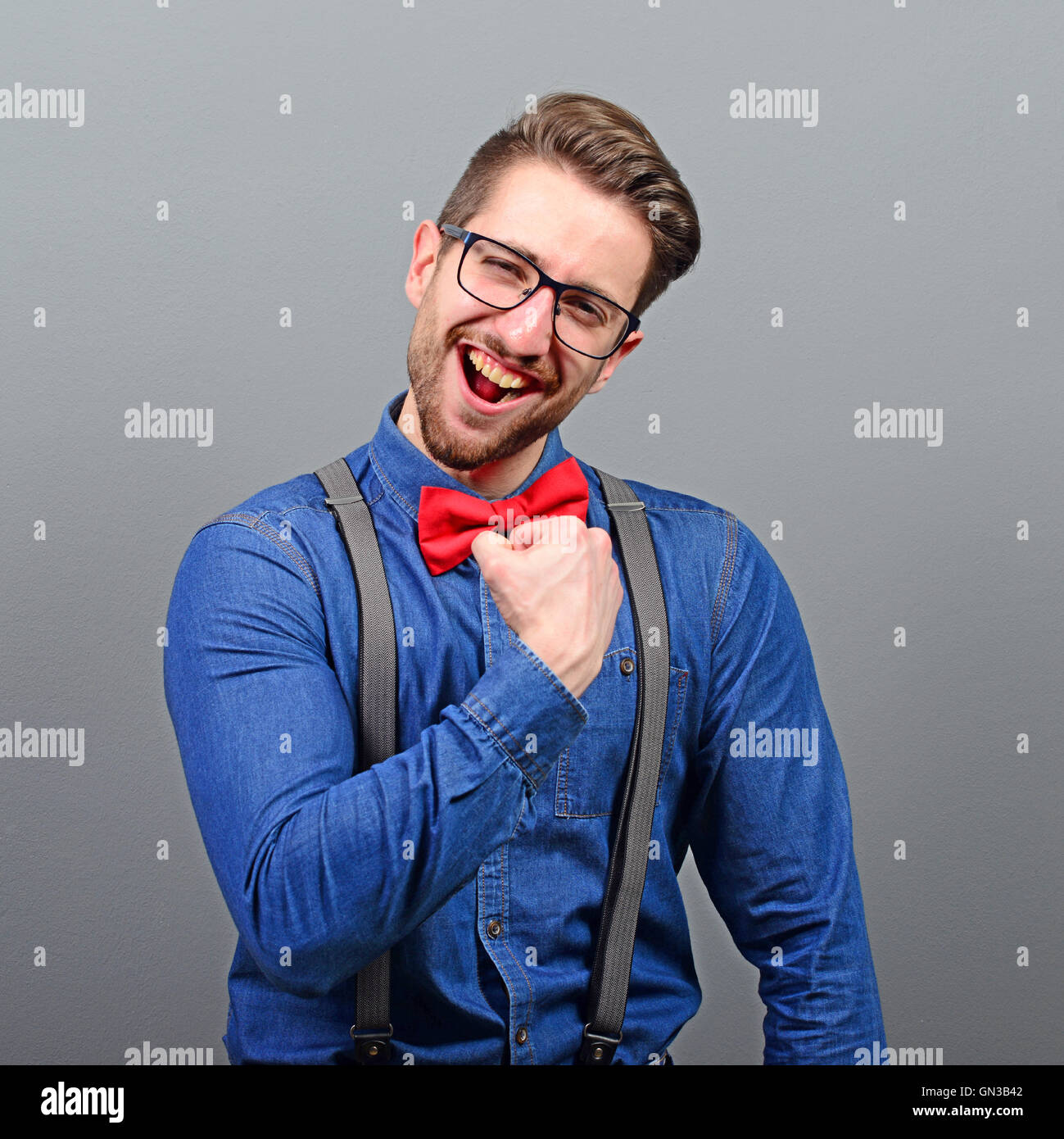 Portrait of ecstatic young man celebrating victory or win against gray ...