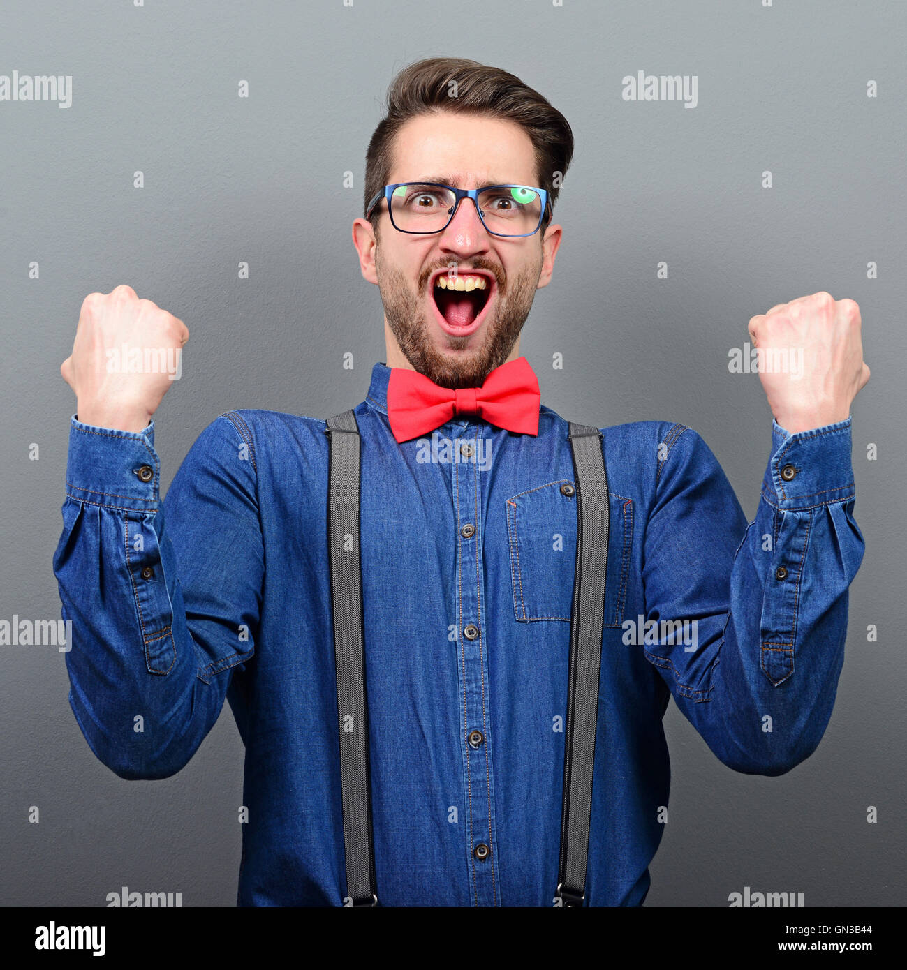 Portrait of ecstatic young man celebrating victory or win against gray ...