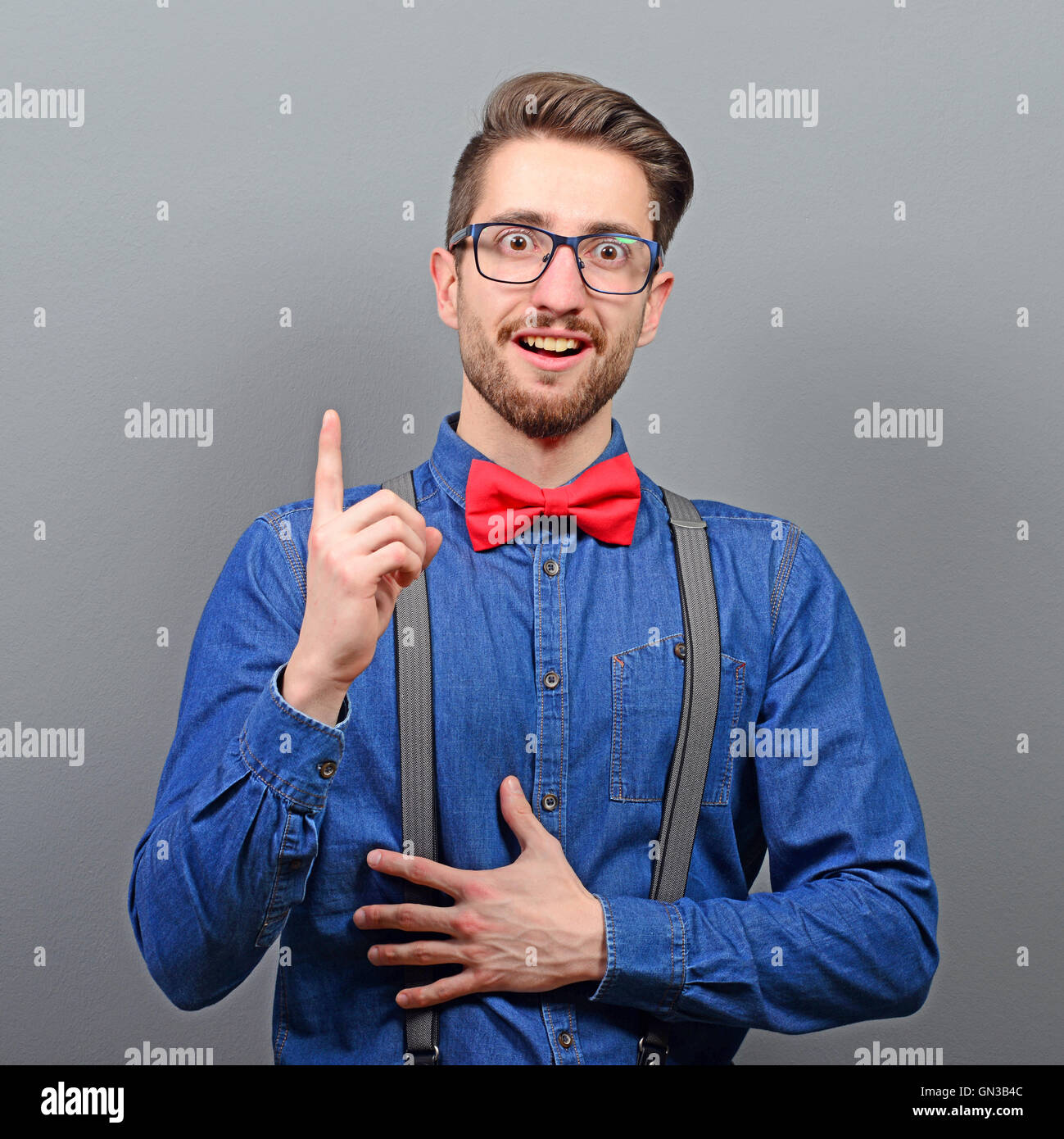 Portrait of man pointing up as a sign of having an idea against gray ...