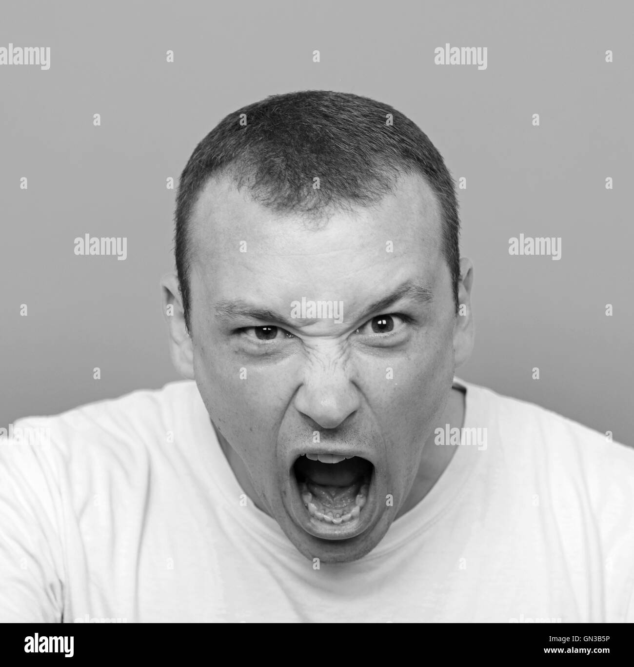 Portrait of angry man screaming against red background Stock Photo - Alamy