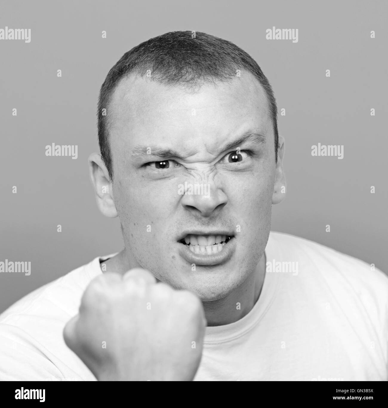Portrait of angry man screaming showing fist against red background ...