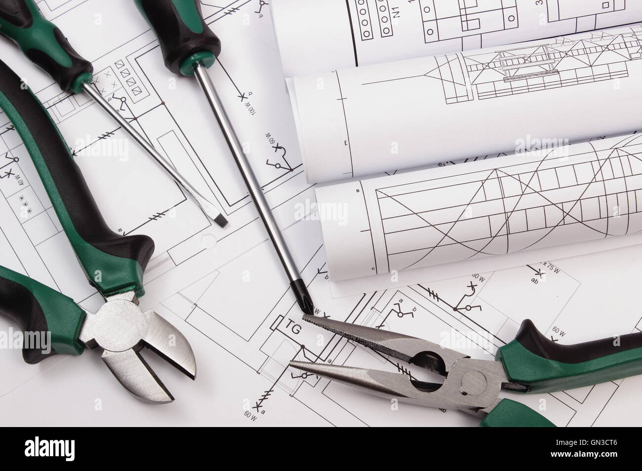 Rolls of diagrams, metal pliers and screwdriver on electrical ...