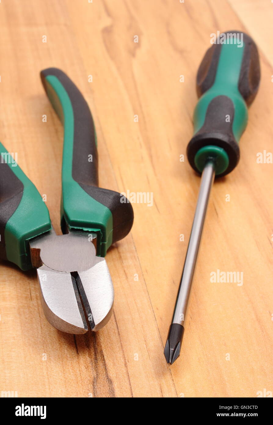 Metal pliers and electrical screwdriver on wooden surface, work tools ...