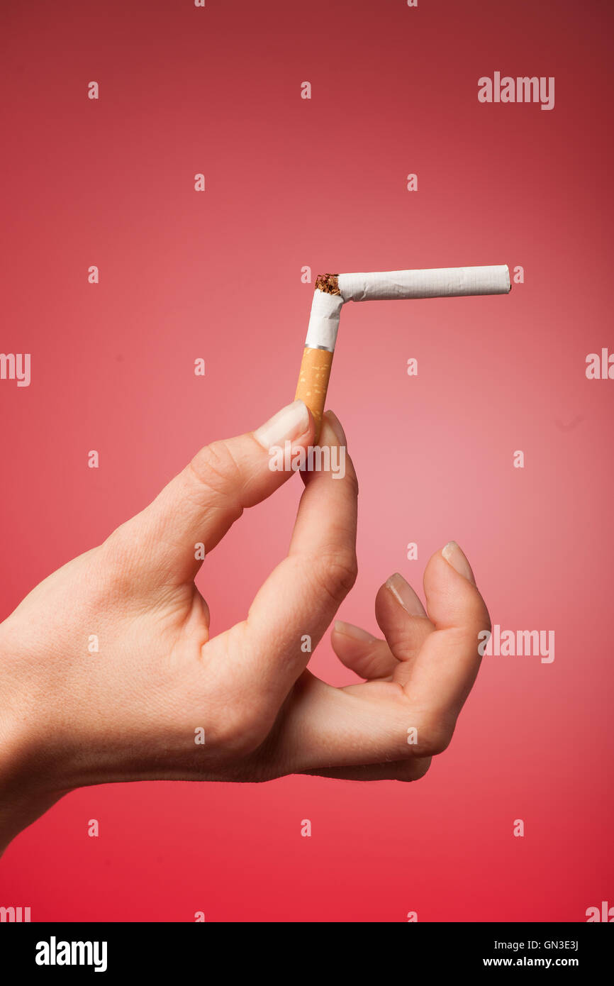 beautiful young woman breaks a cigarette as a gesture for quit smoking ...