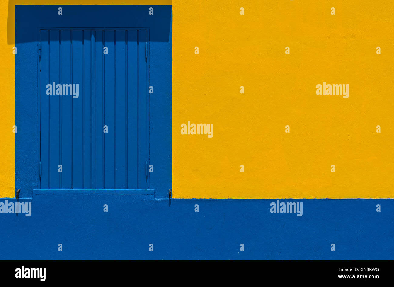 A blue wooden window closed on a yellow and blue wall in a european ...