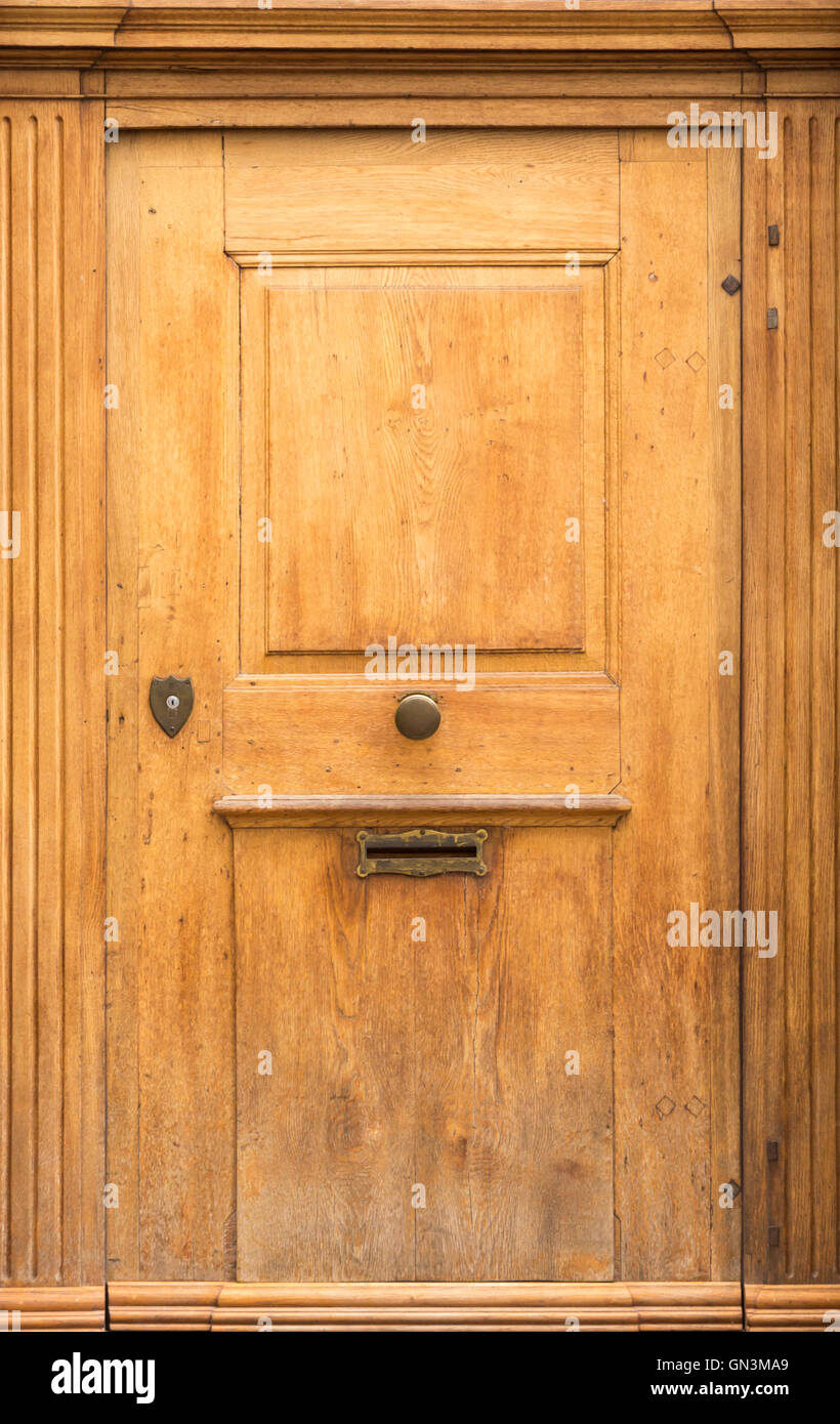 Old light brown wooden door with round metal knob and mail box slit ...