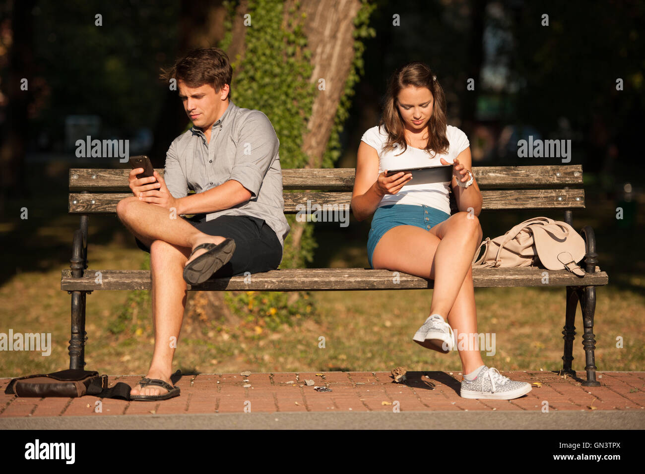 Young couple distracted with communication technology tablet and smart ...