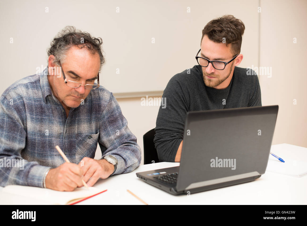 Young man teaching eldery man of usage of computer. Intergenerational ...