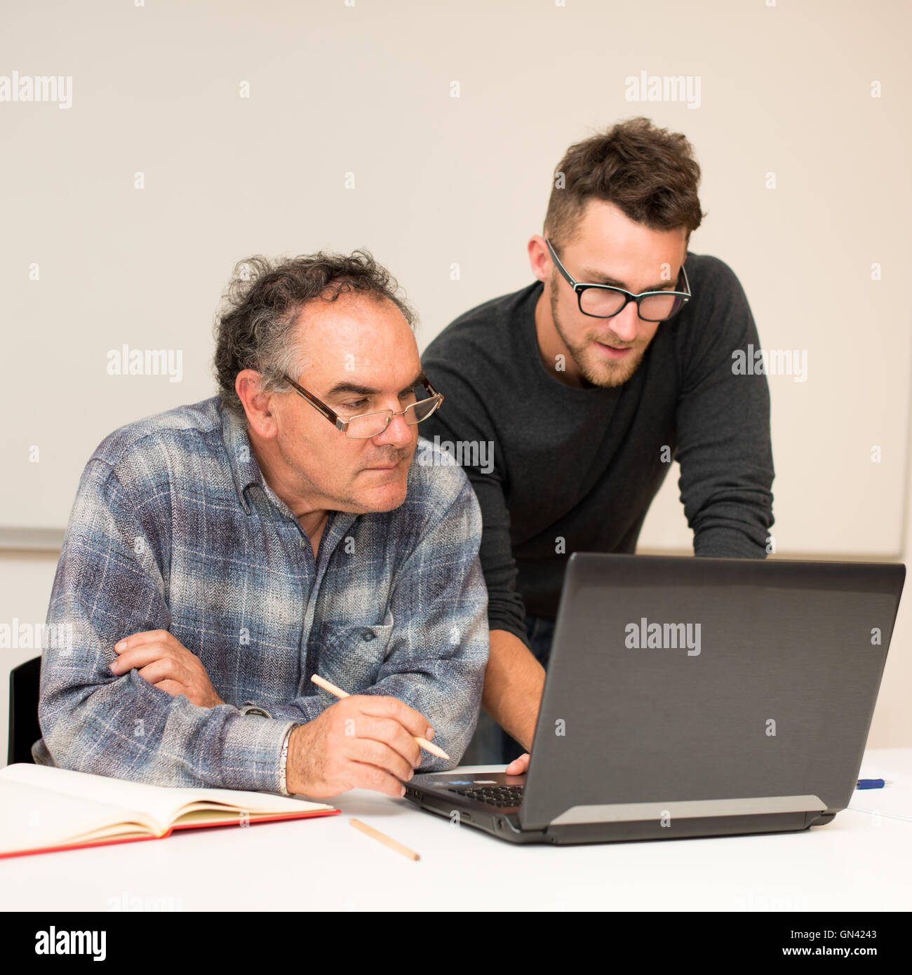 Young man teaching eldery man of usage of computer. Intergenerational ...