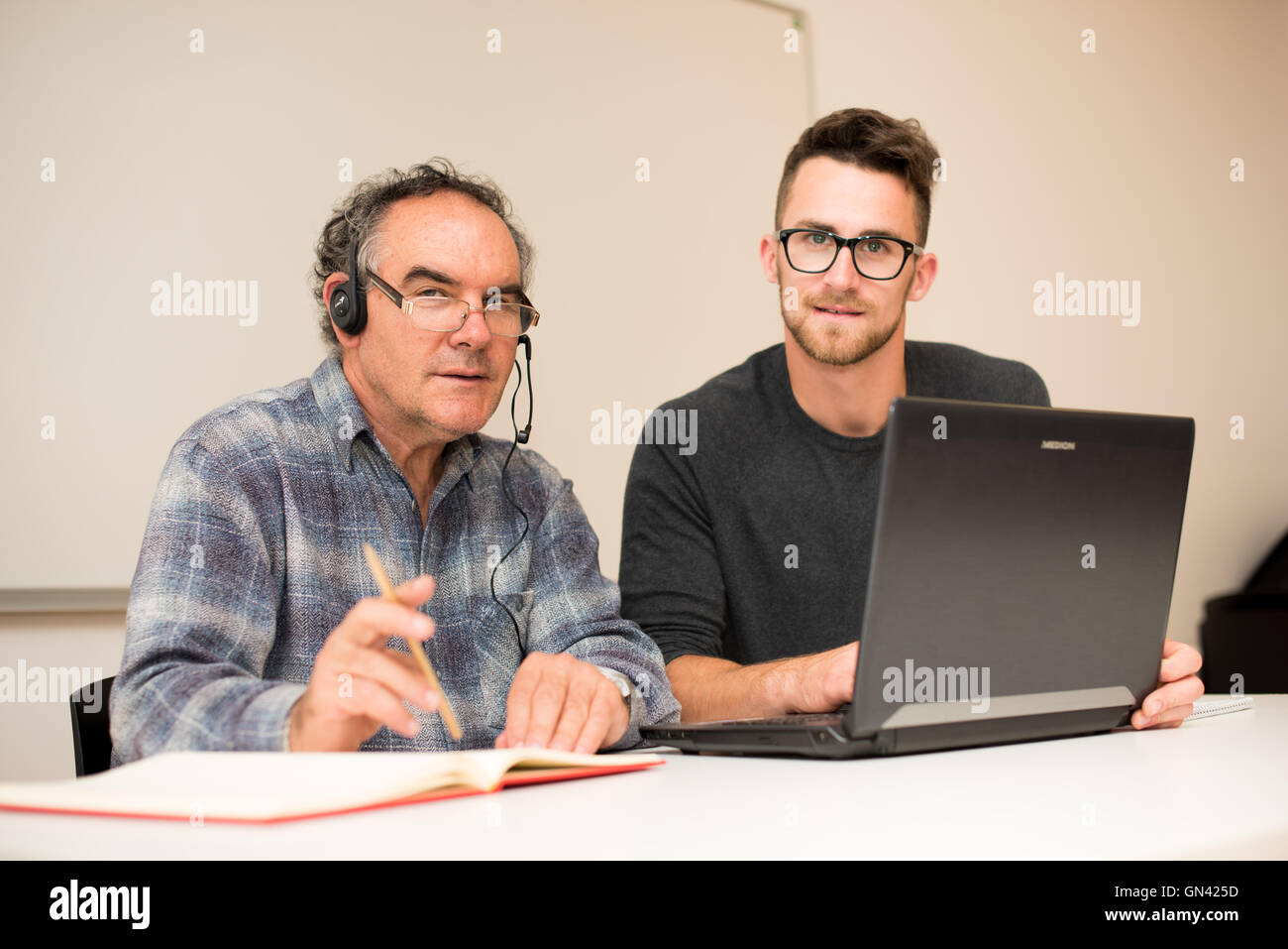 Young man teaching eldery man of usage of computer. Intergenerational ...
