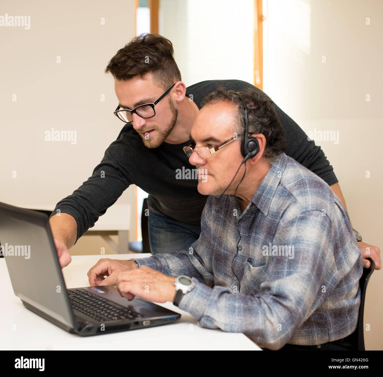 Young man teaching eldery man of usage of computer. Intergenerational ...