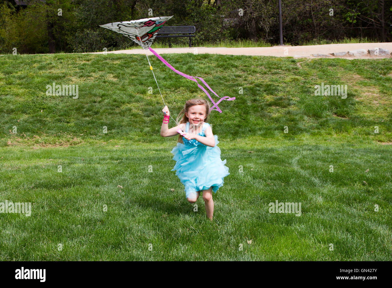 Young Caucasian girl laughing as she runs trying to fly kite Stock ...