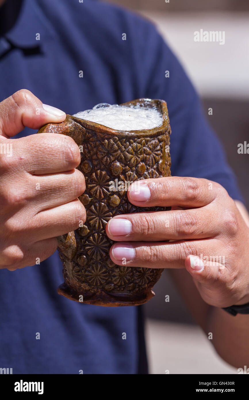 close up of an adult males hands holding cup with Peruvian white Chicha ...