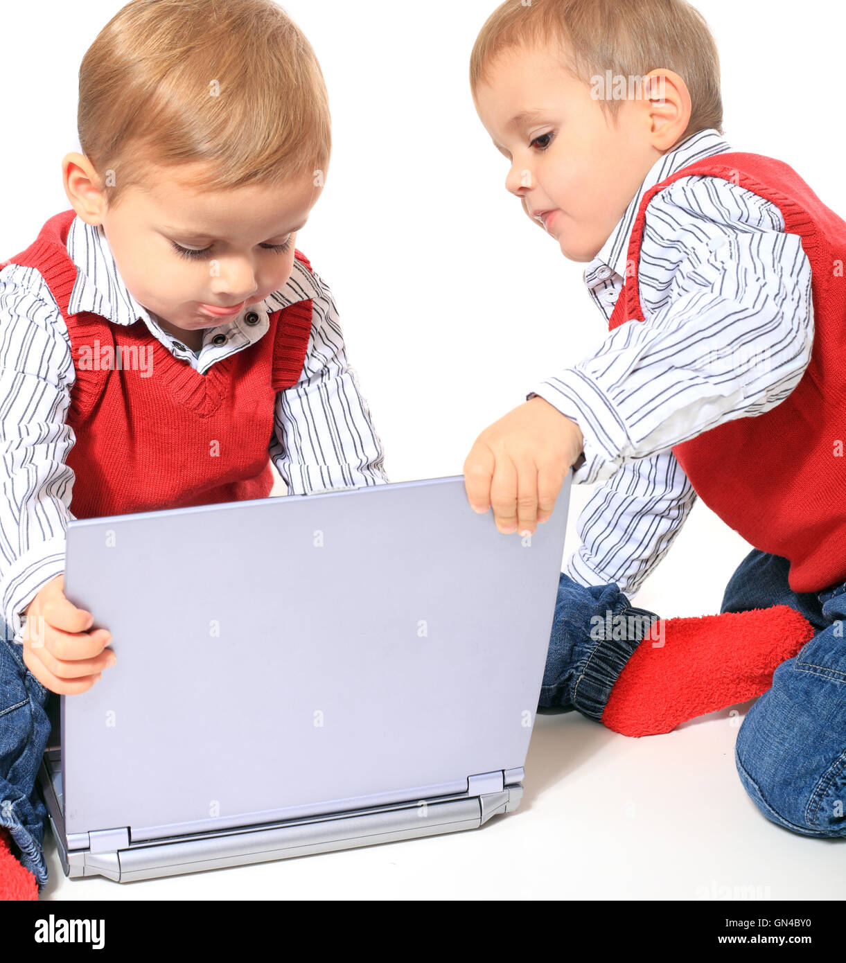 Twins playing with laptop Stock Photo - Alamy