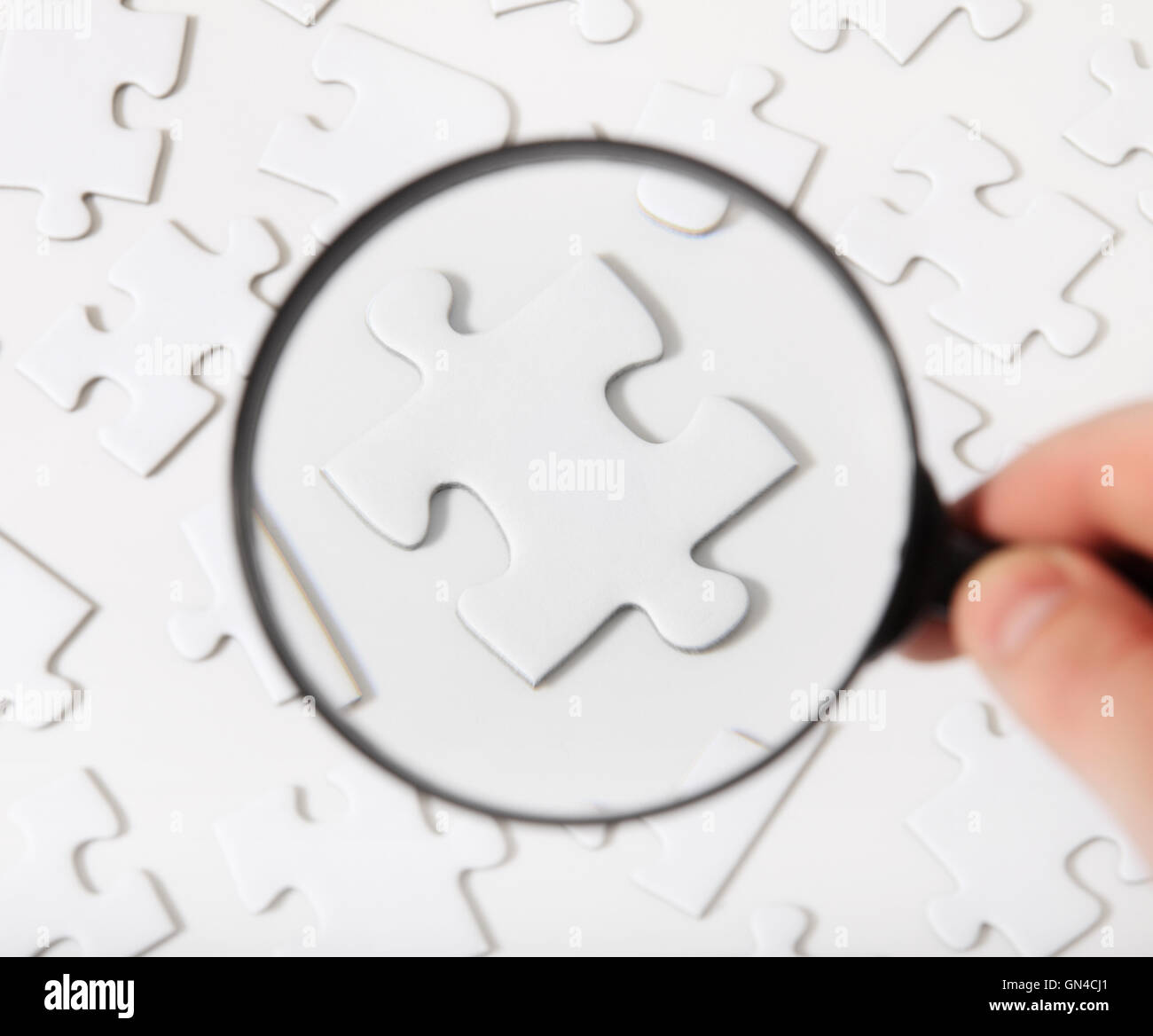 person using a magnifier to check piece of a puzzle Stock Photo - Alamy