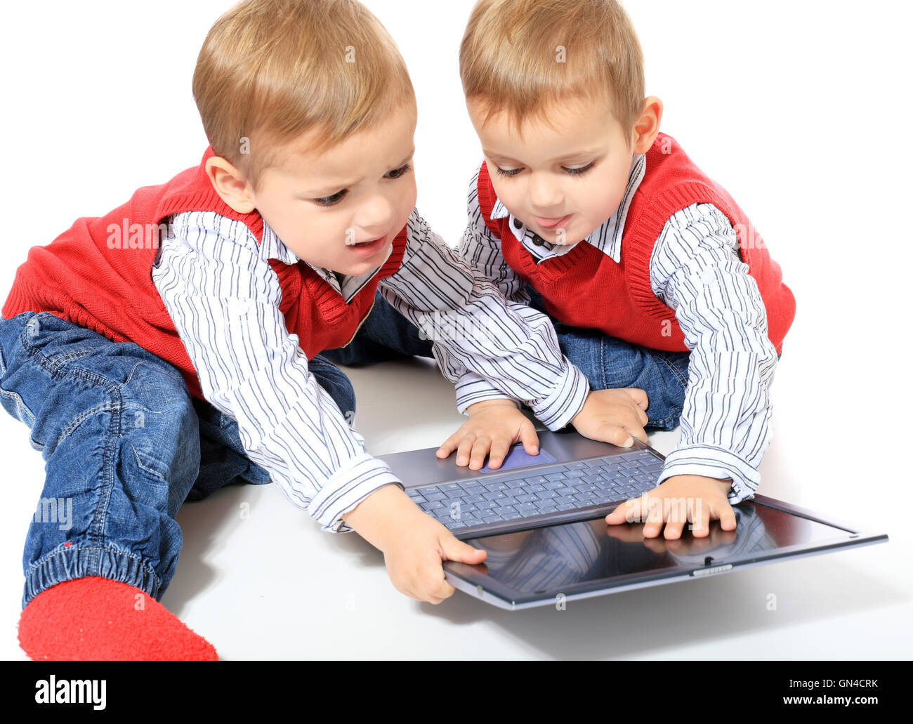 Twins playing with laptop Stock Photo - Alamy