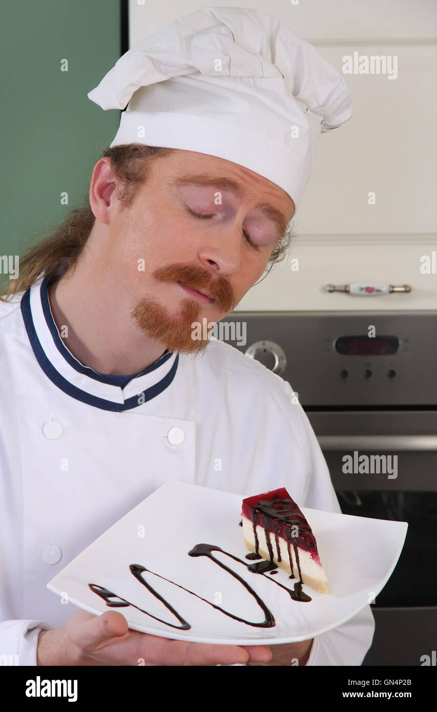Funny young chef smelling a piece of cake Stock Photo - Alamy