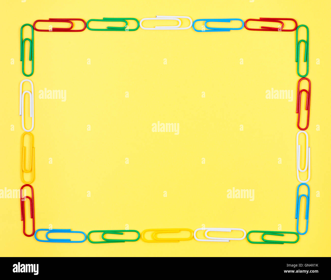 Frame of colorful paper clips on yellow background Stock Photo - Alamy