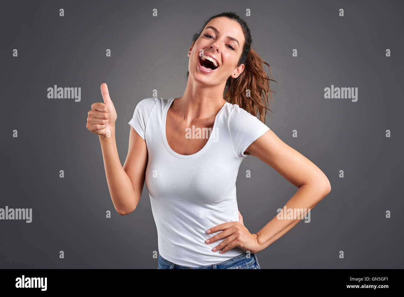 A beautiful young woman smiling and showing thumbs up Stock Photo - Alamy