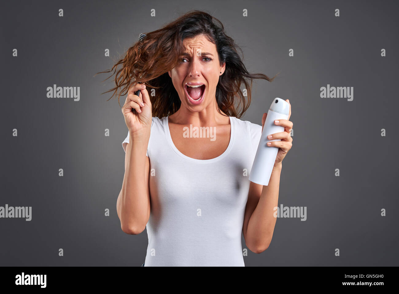 A beautiful young woman screaming while brushing her hair and holding a ...