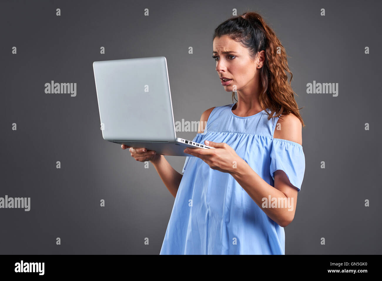 A beautiful young woman standing and felling surprised while grabbing a ...