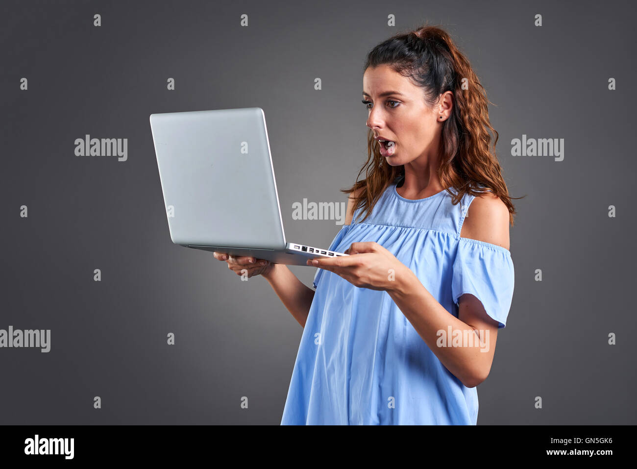 A beautiful young woman standing and feeling surprised while grabbing a ...