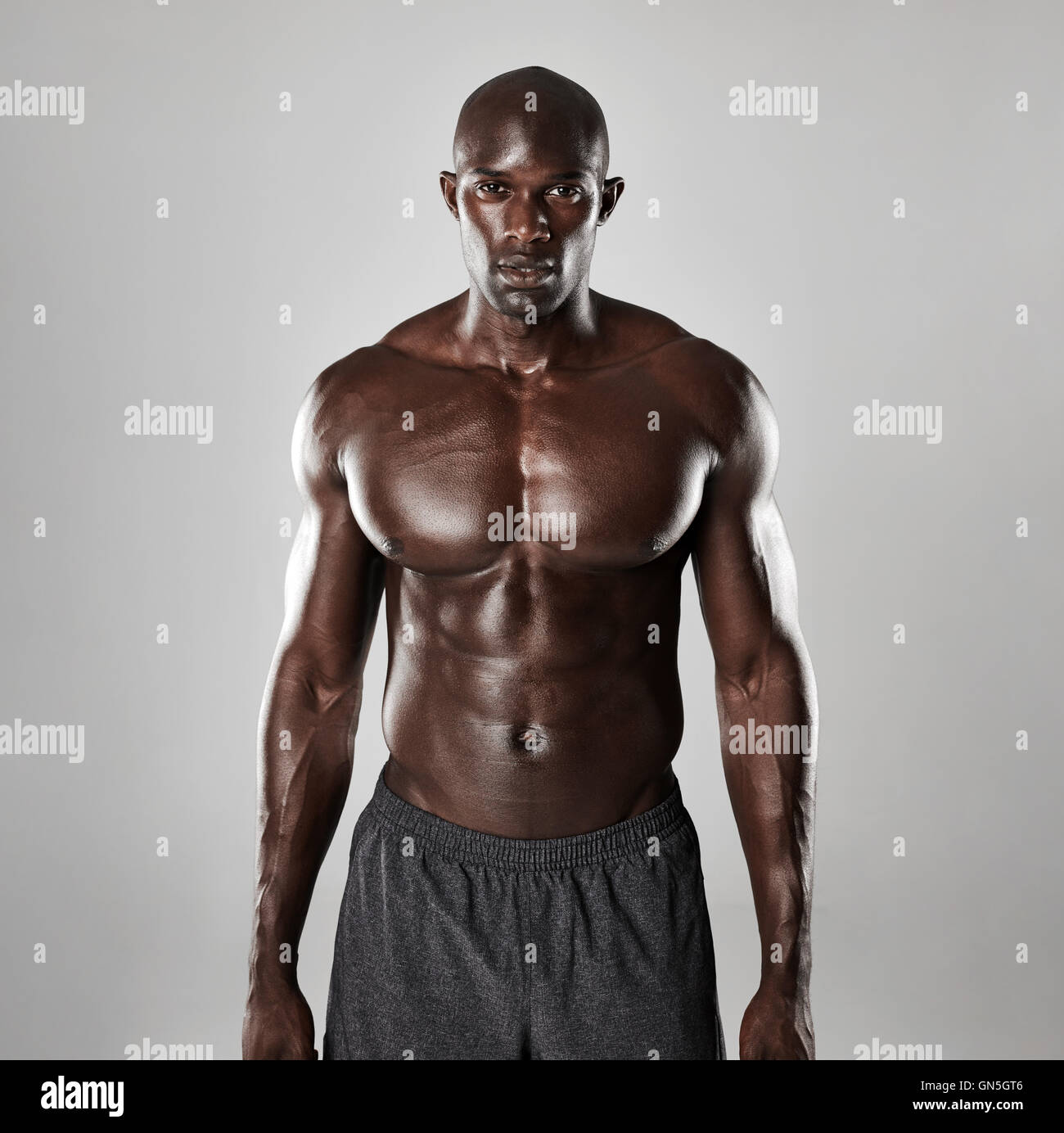 Portrait of a strong afro american man showing off his physique against ...