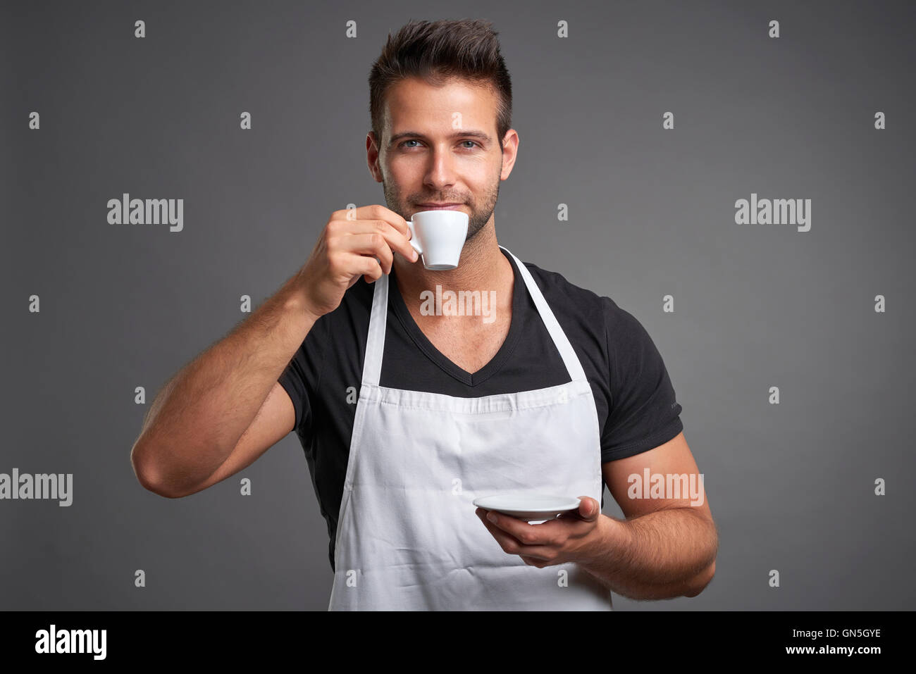 A young barista man smiling and enjoying a cup of coffee Stock Photo ...
