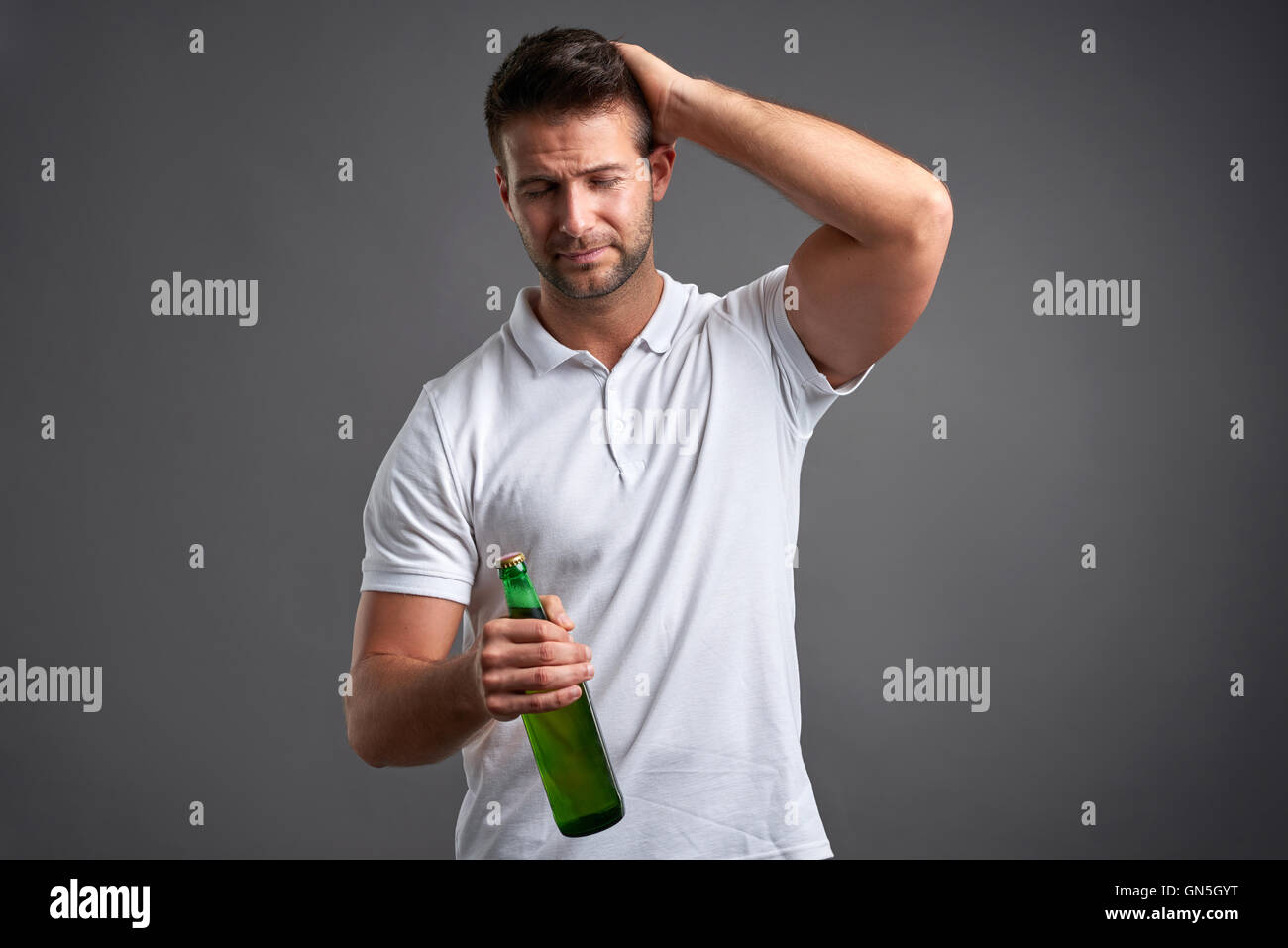 A handsome young man feeling desperate and grabbing his head while ...